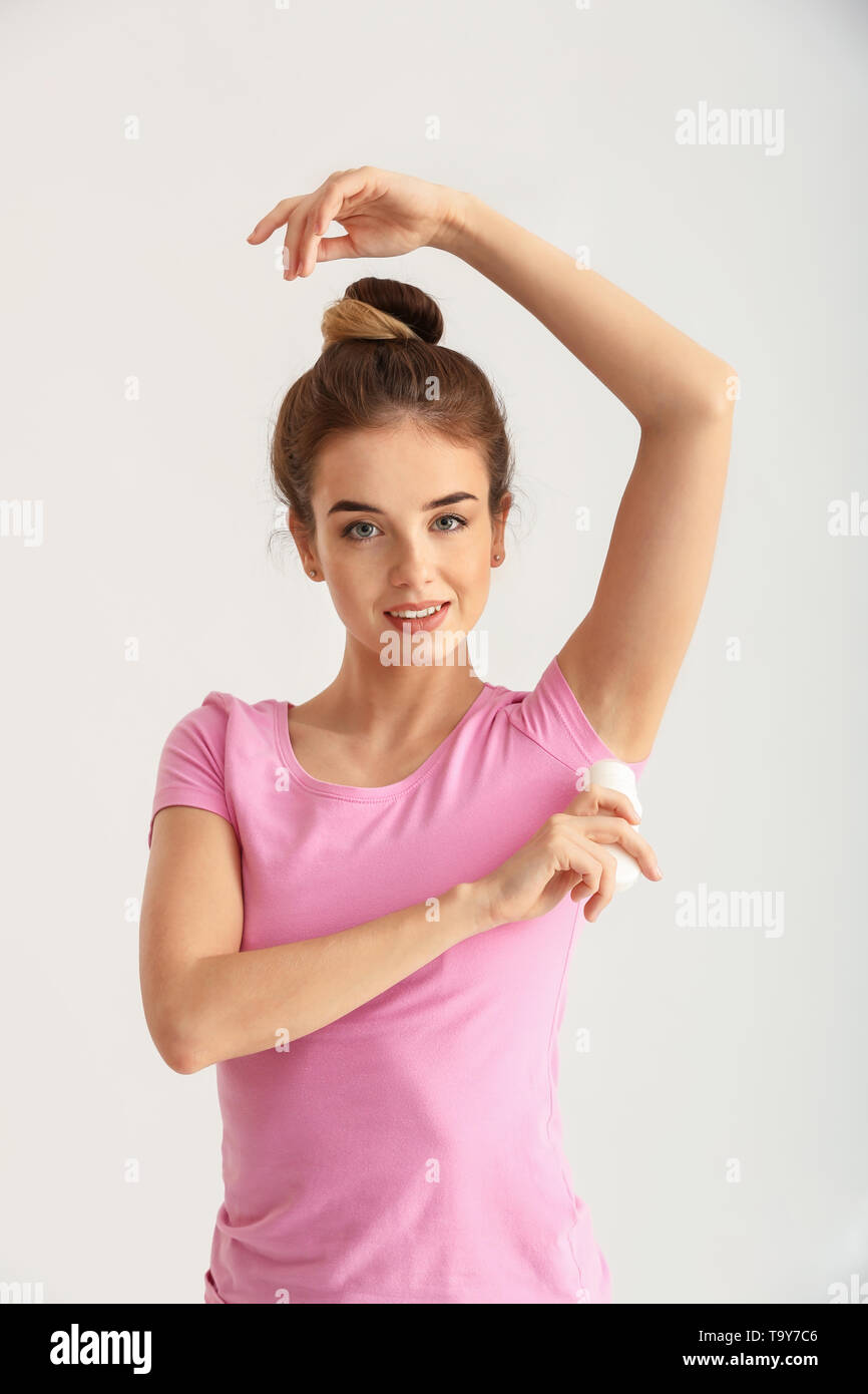 Beautiful young woman with deodorant on light background Stock Photo ...
