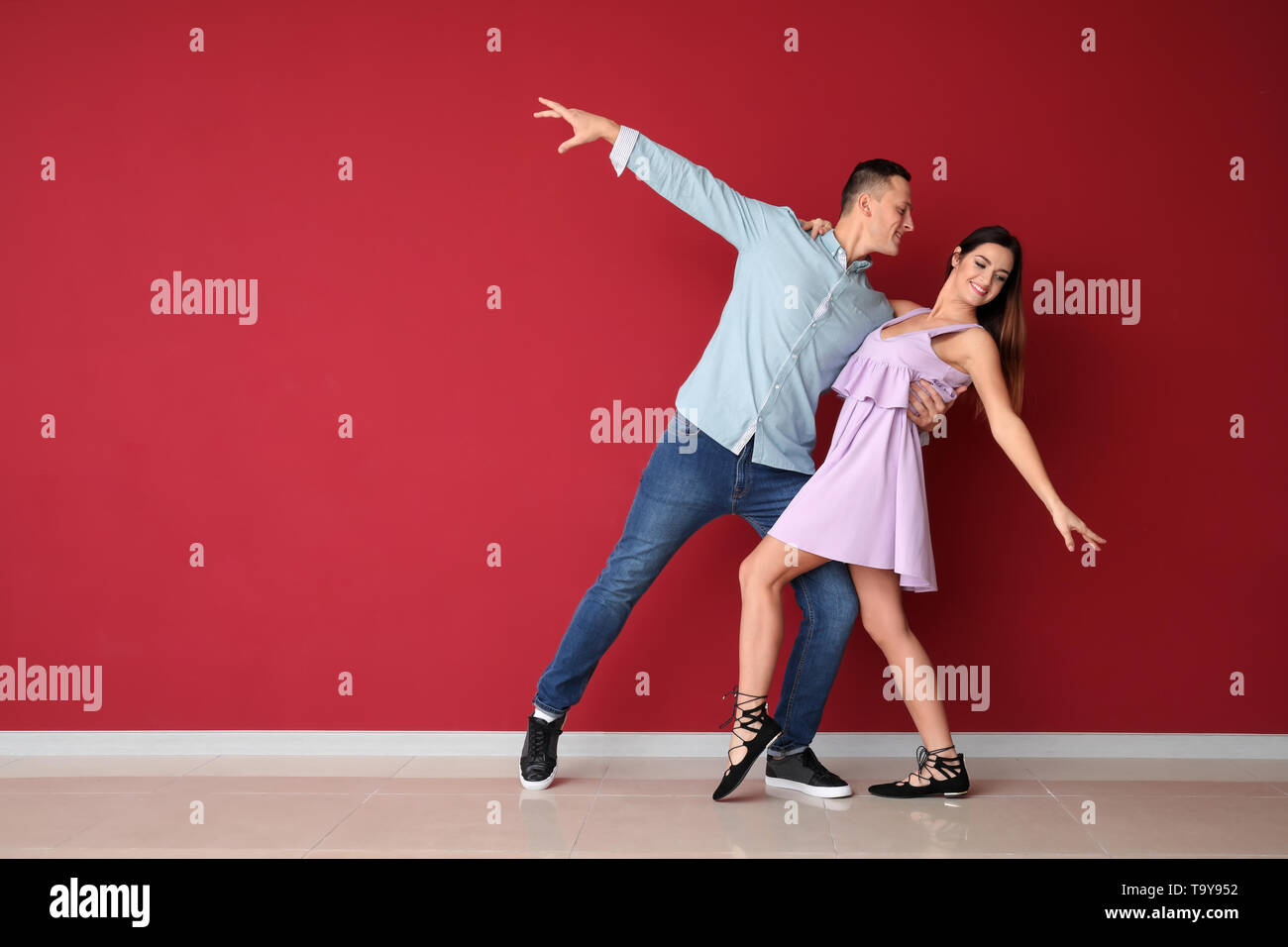 Young couple dancing near color wall Stock Photo - Alamy
