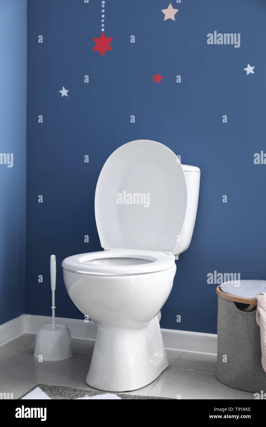 Modern ceramic toilet bowl near color wall in restroom Stock Photo - Alamy