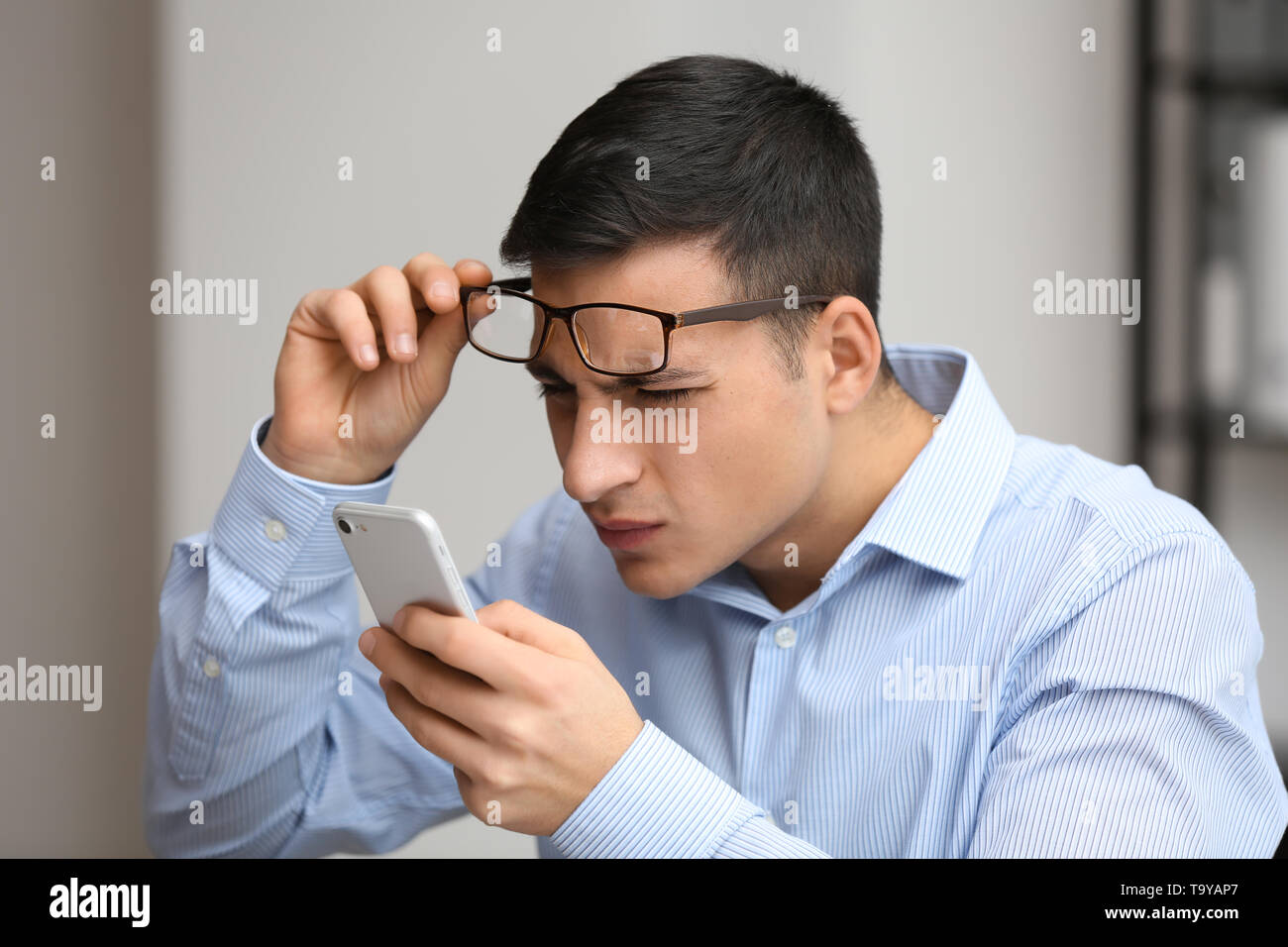 Young man with bad sight trying to read message on screen of mobile ...