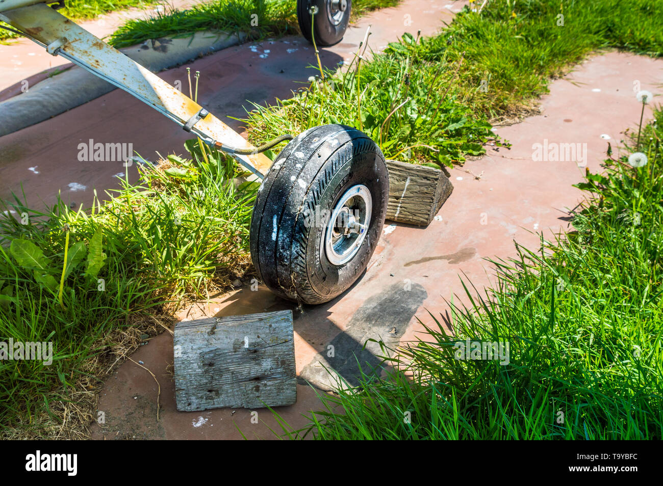 Old small single engine airplane wheel and wooden chocks on parking pad ...