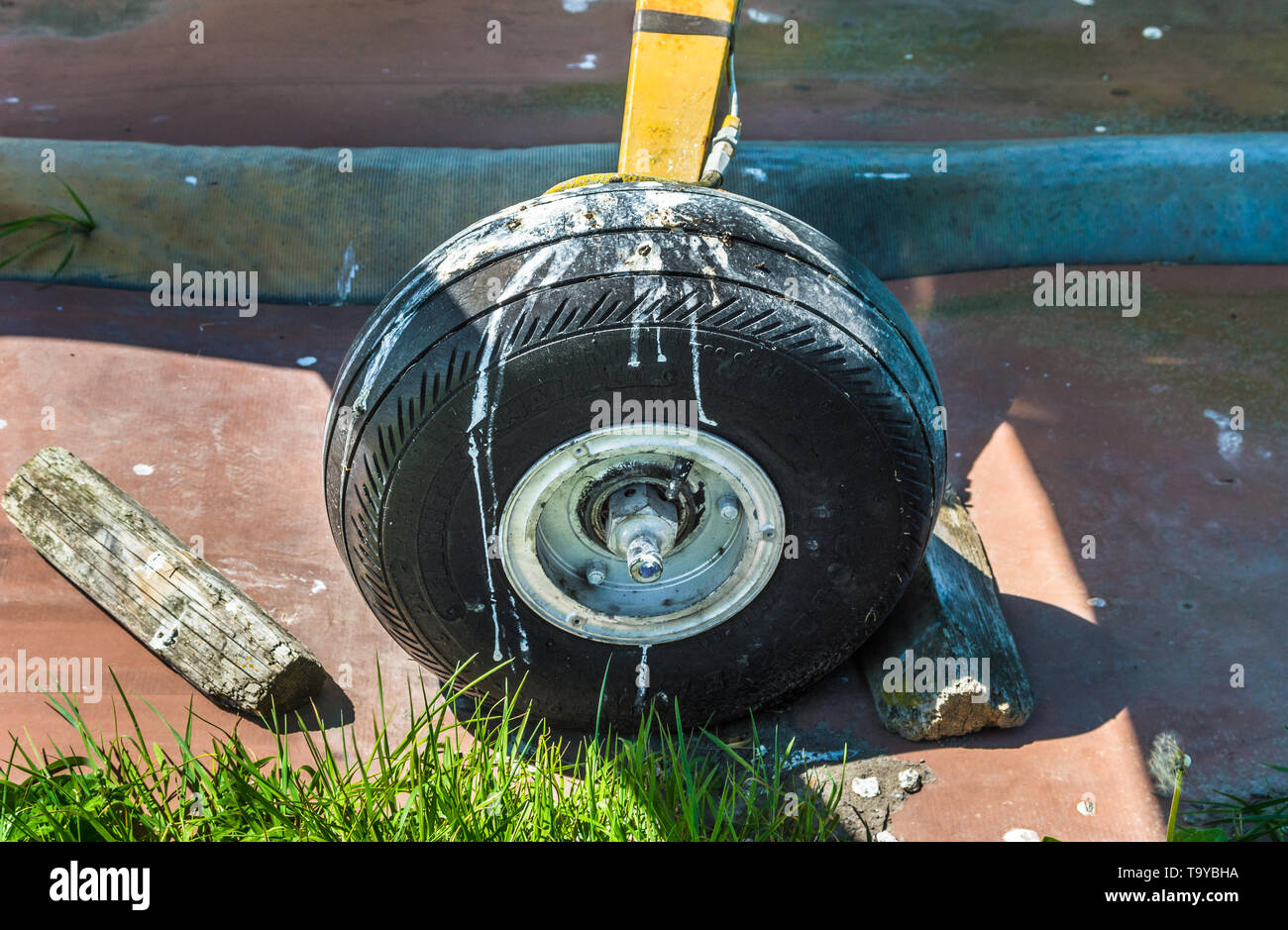 Old small single engine airplane wheel and wooden chocks on parking pad ...