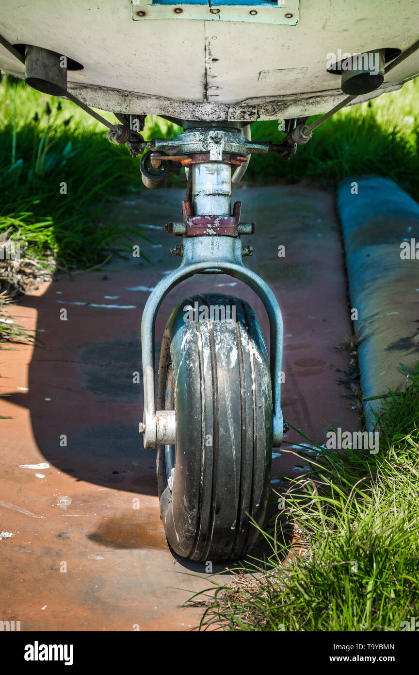 Old small single engine airplane landing gear on grassy parking pad on ...