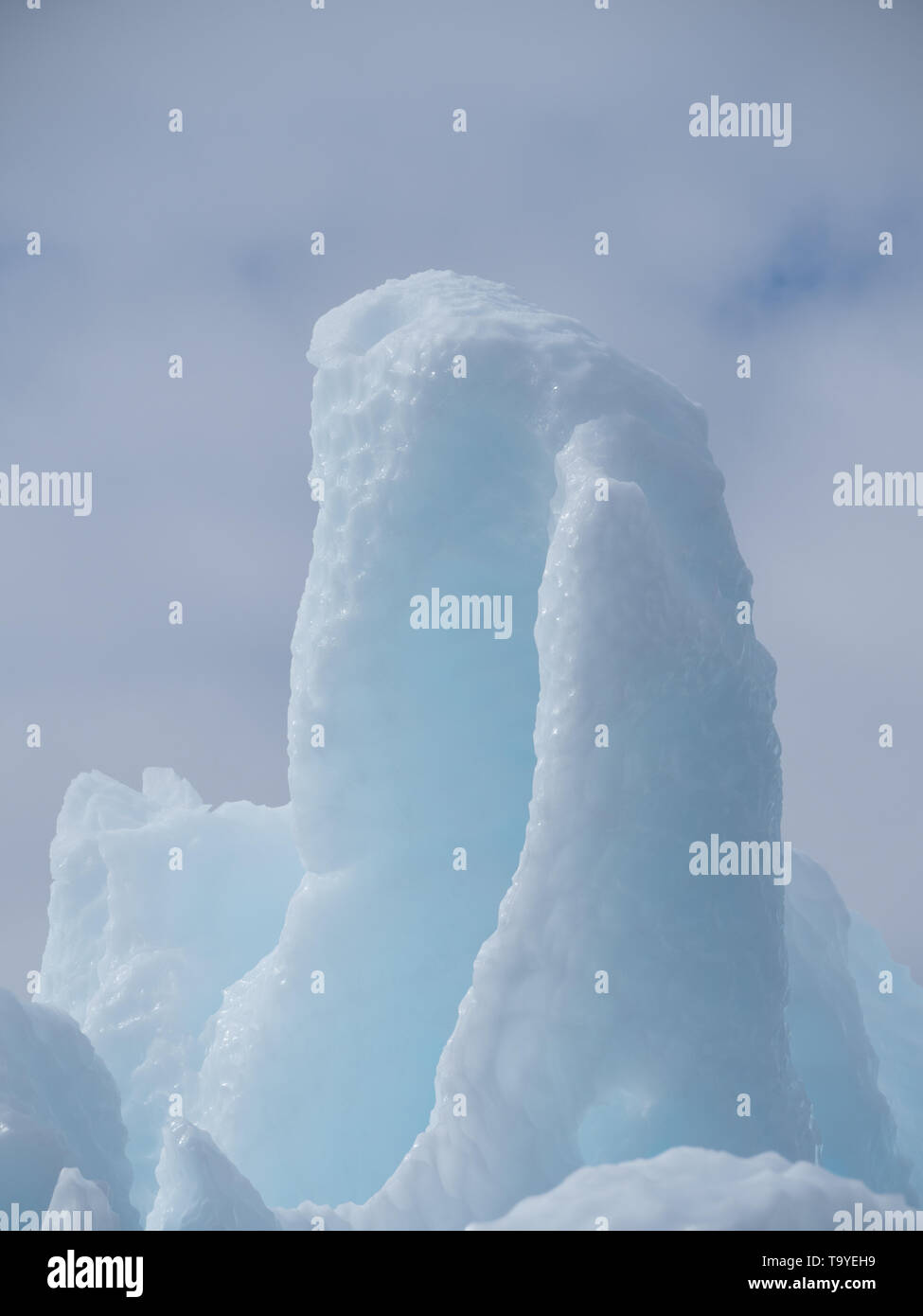 Vertical baby blue iceberg with pock marks or divots glistening in the ...