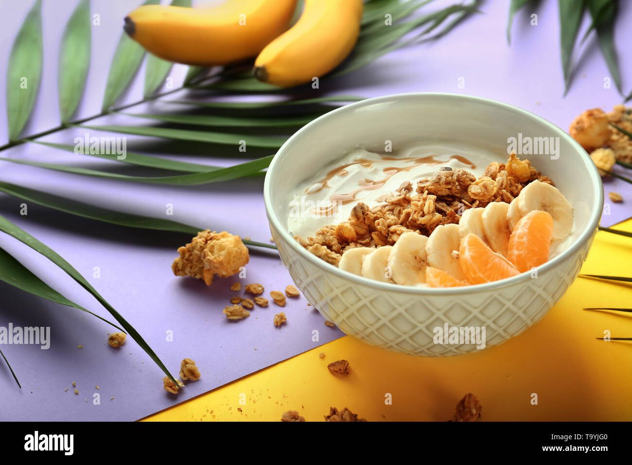 Tasty granola with yogurt and fruits in bowl on color background Stock ...