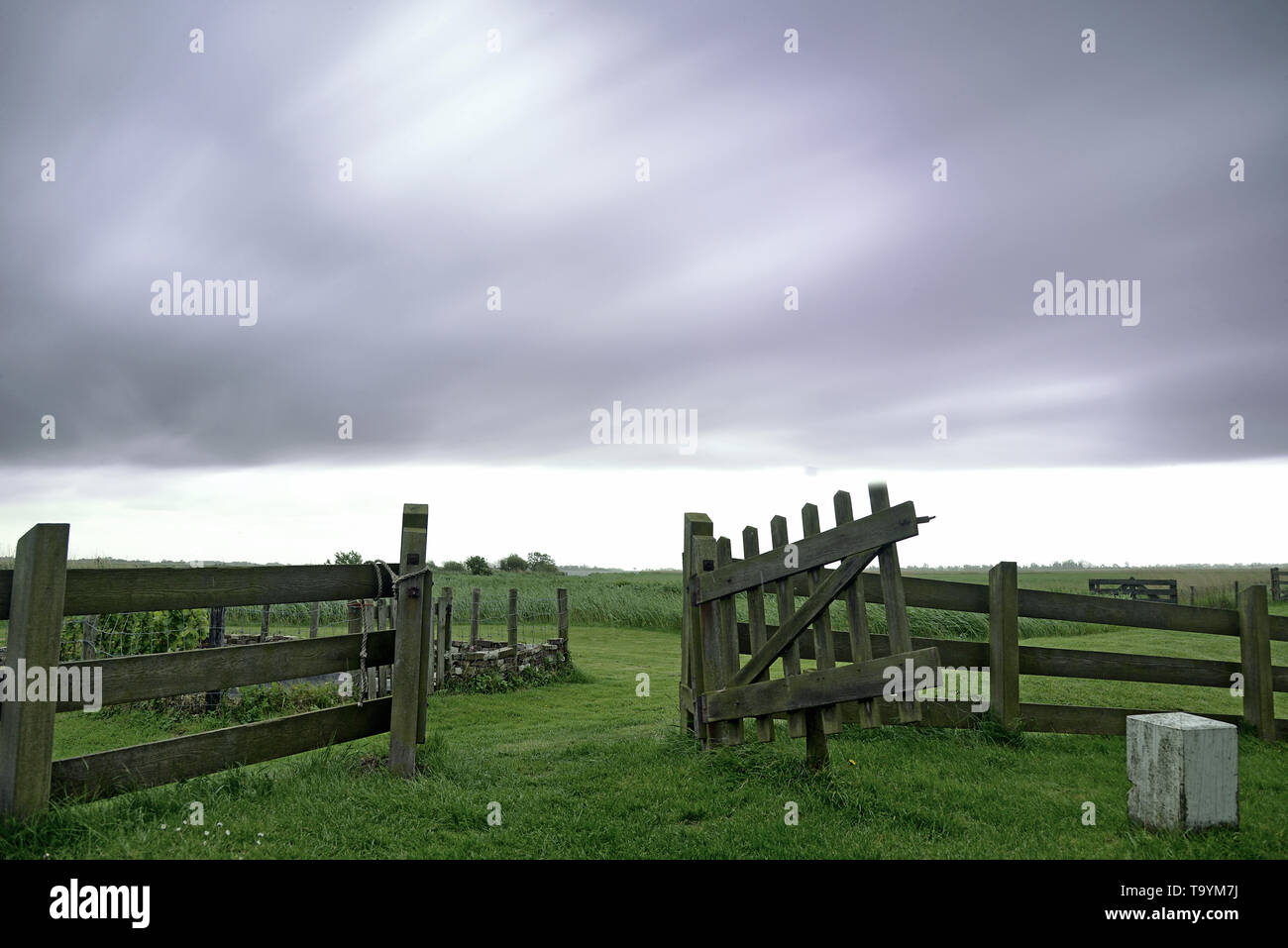 Beautiful long exposure of clouds passing overhead with a wooden fence ...