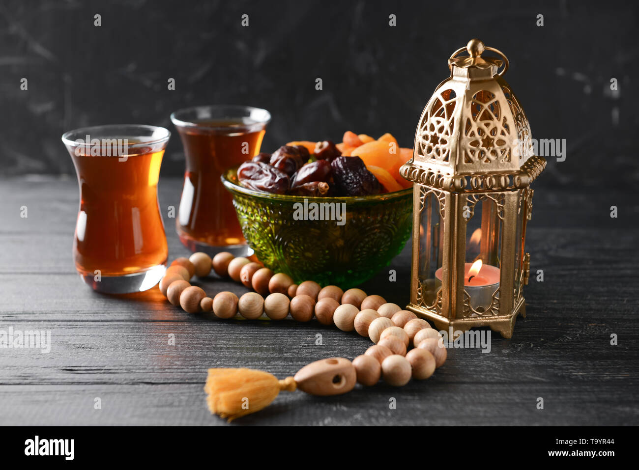 Muslim lamp, dried fruits, tea and tasbih on wooden table Stock Photo ...
