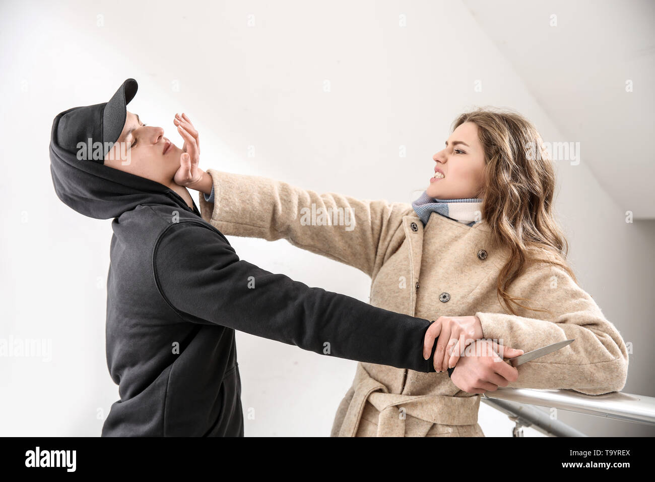 Young woman defending herself from thief in stairway Stock Photo - Alamy