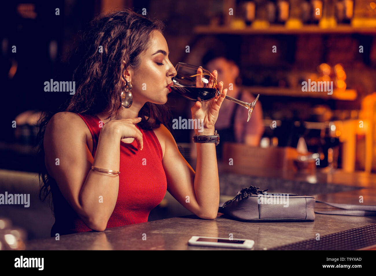 Woman wearing watch holding glass of wine and drinking Stock Photo - Alamy