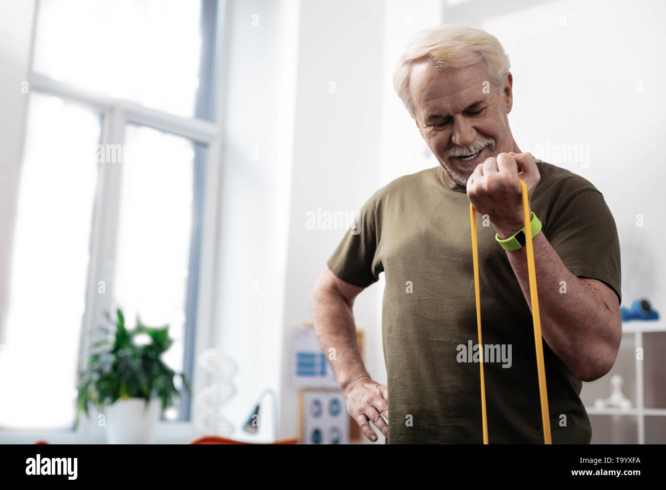 Joyful strong man stretching his arm with a rubber band Stock Photo - Alamy