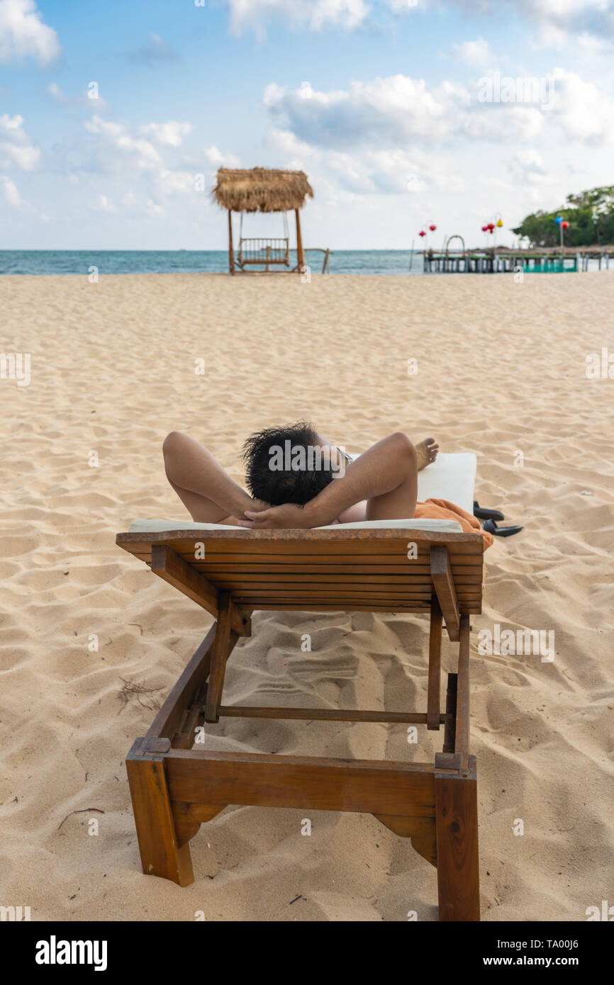 Vertical photo of Asian man sunbath and relax at beach Stock Photo - Alamy