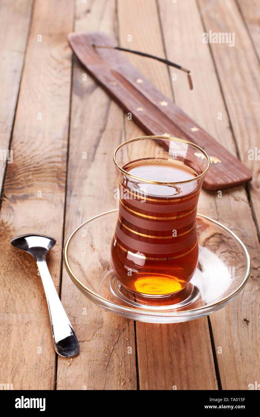 Turkish apple tea in traditional glass and plate on wooden background ...