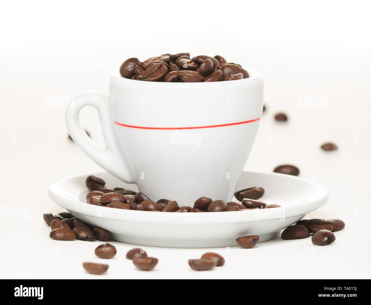 Cup with heap of coffee beans on white background Stock Photo - Alamy