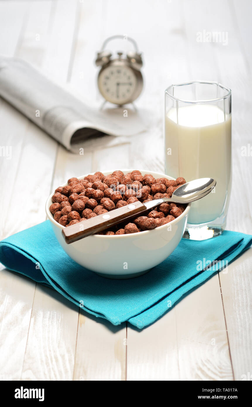 Chocolate corn flakes on wooden plank table with alarm clock and ...