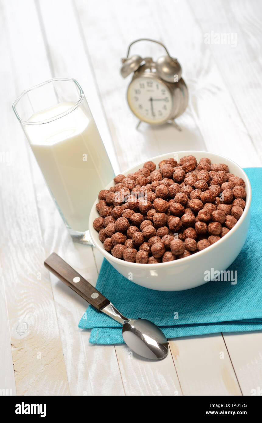 Chocolate corn flakes on wooden plank table with alarm clock and ...