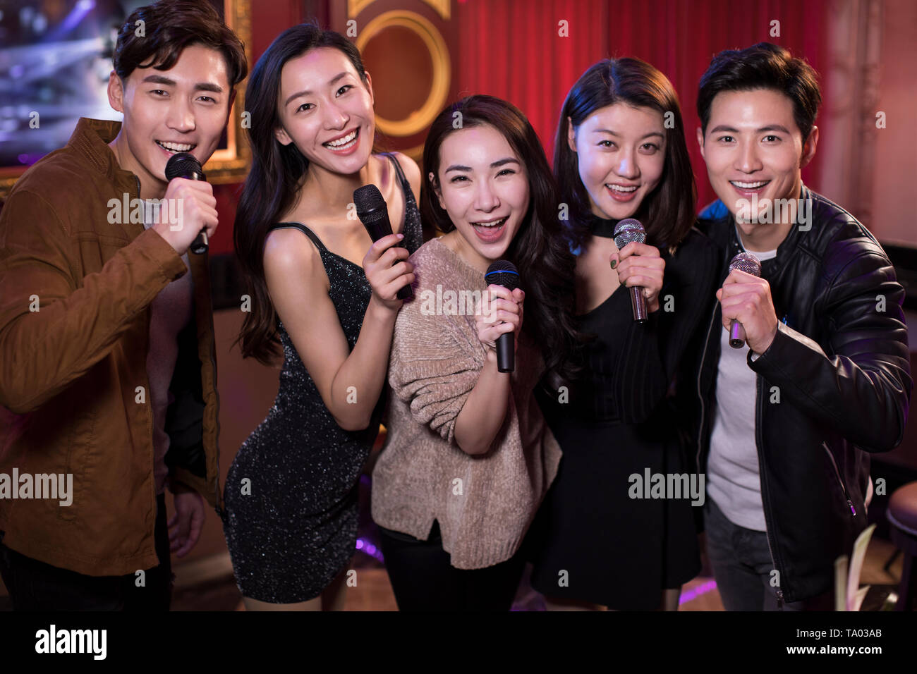 Happy friends singing karaoke in nightclub Stock Photo - Alamy
