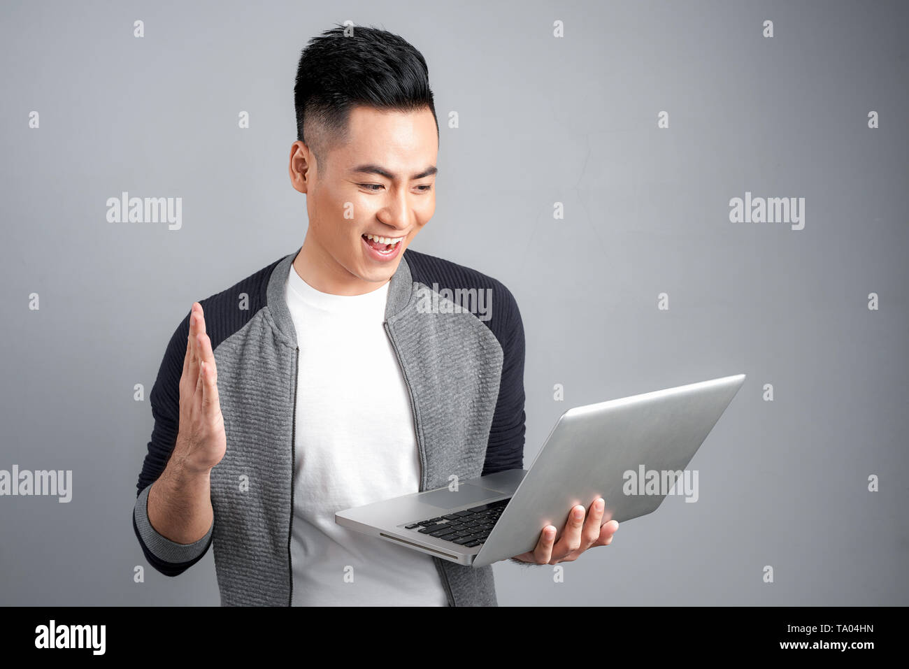 Excited happy asian man looking at laptop computer screen and ...
