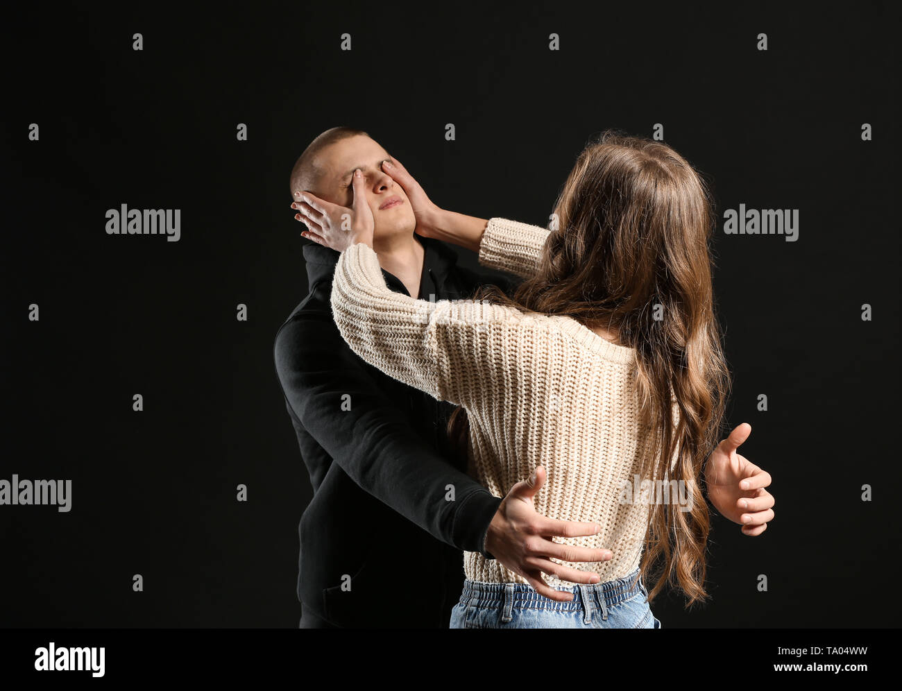 Young woman defending herself from attack by thief on dark background ...