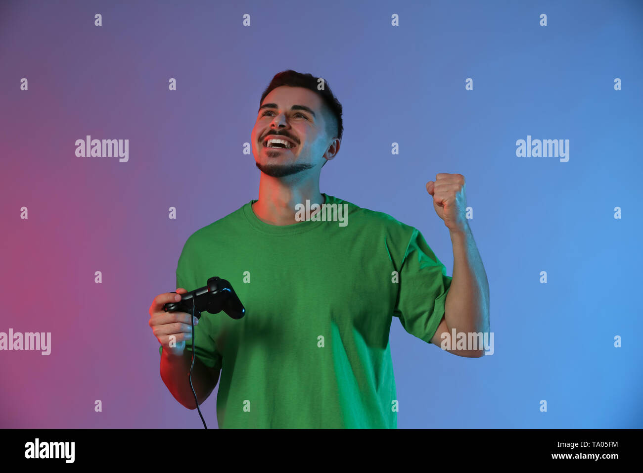 Happy young man after winning video game on color background Stock ...