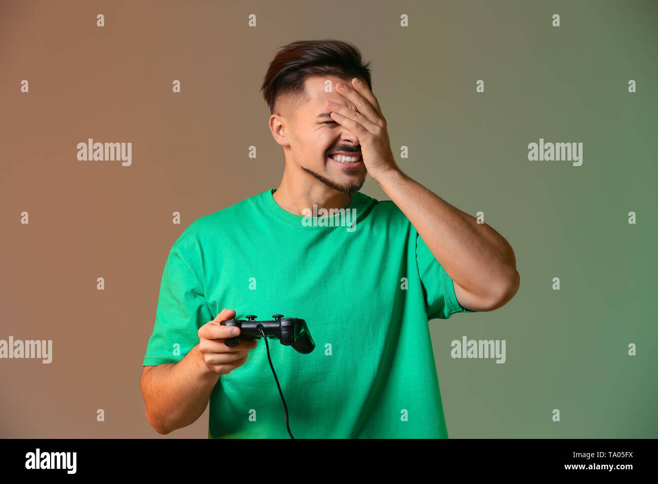 Young man after losing video game on color background Stock Photo - Alamy