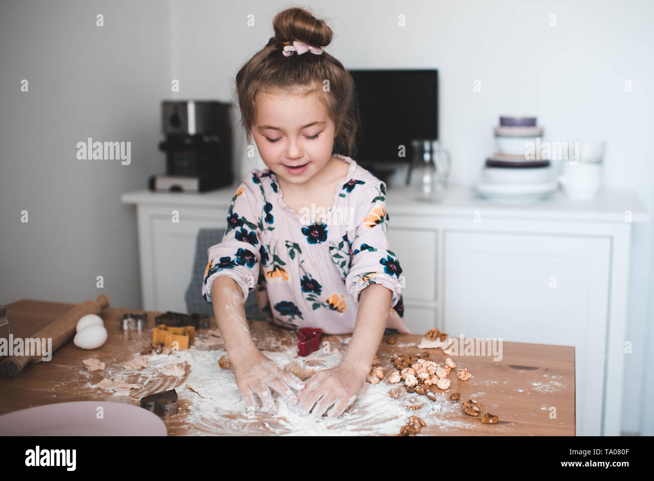 Smiling kid girl 4-5 year old making cookies with almonds in kitchen ...