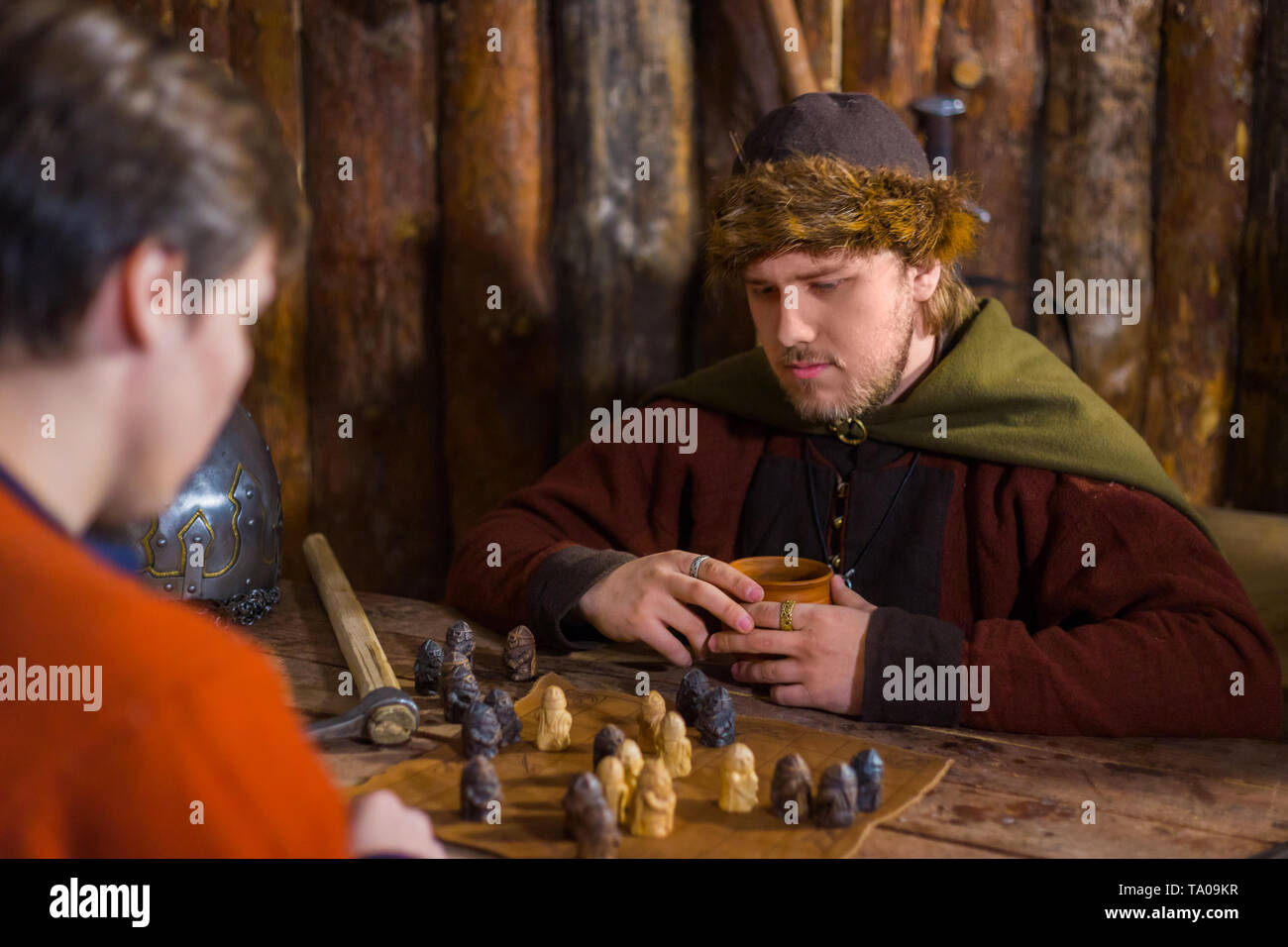 Portrait of man in russian ethnic suit playing board game like chess ...