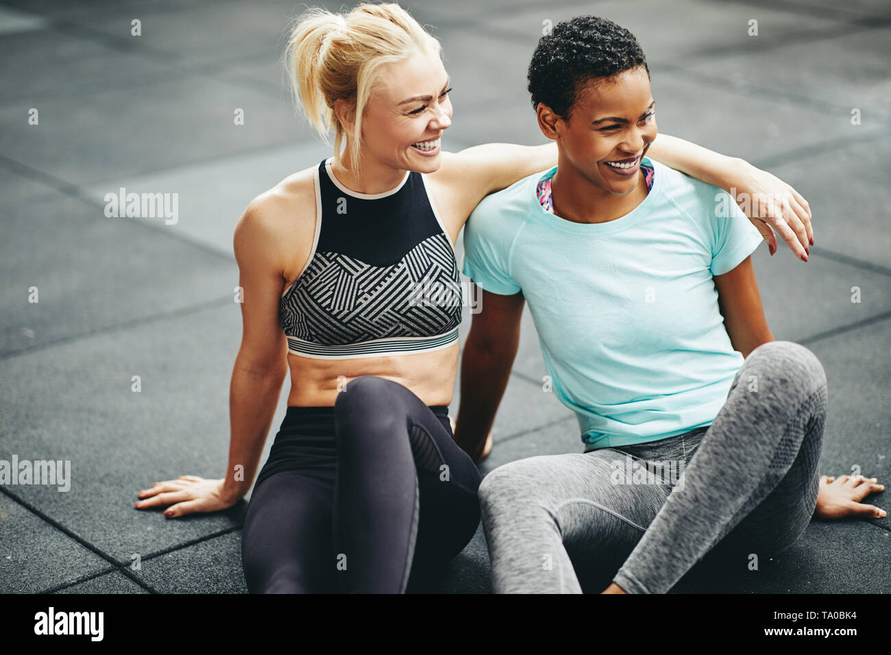 Two fit young female friends in sportswear laughing after a workout ...