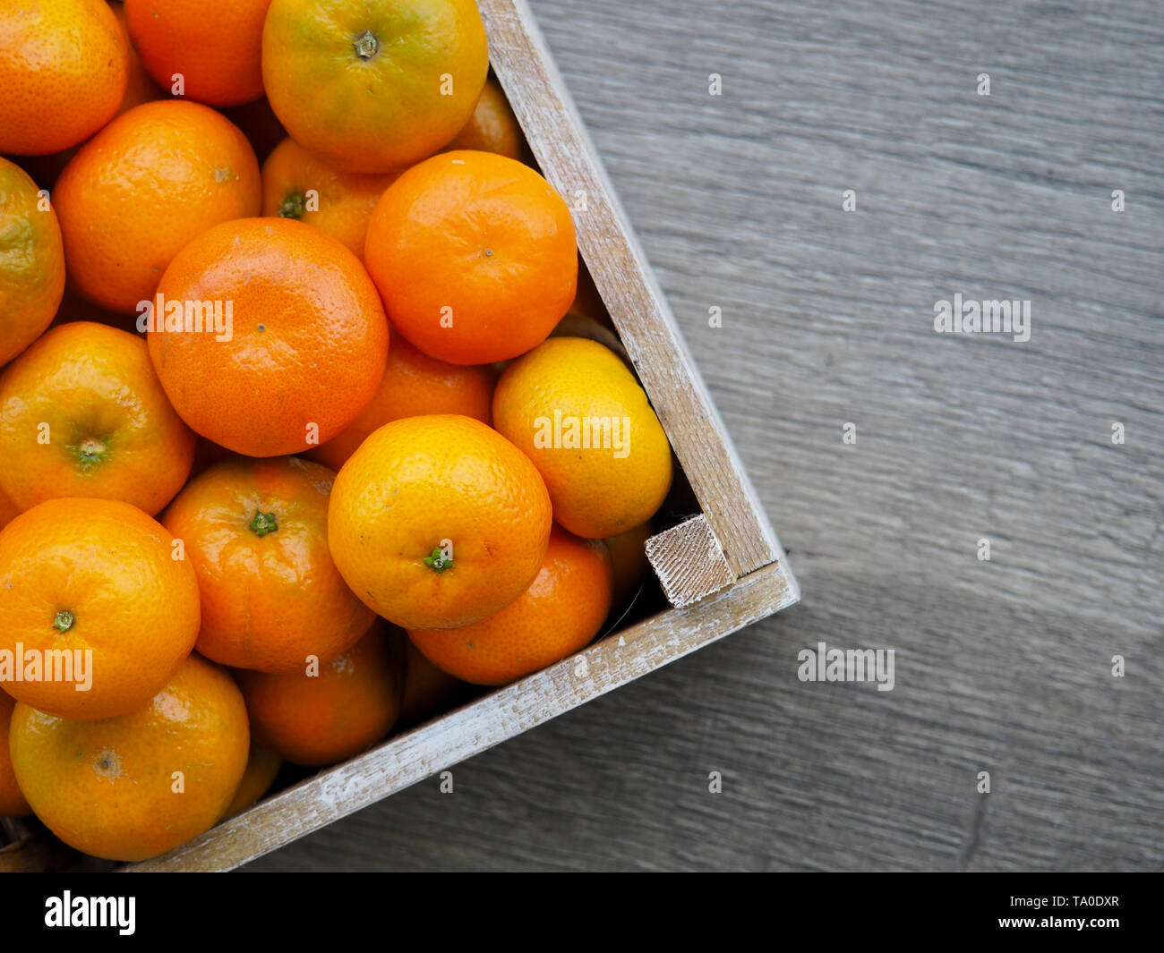 Fresh tangerines in an old box . On wooden background. Free space for ...