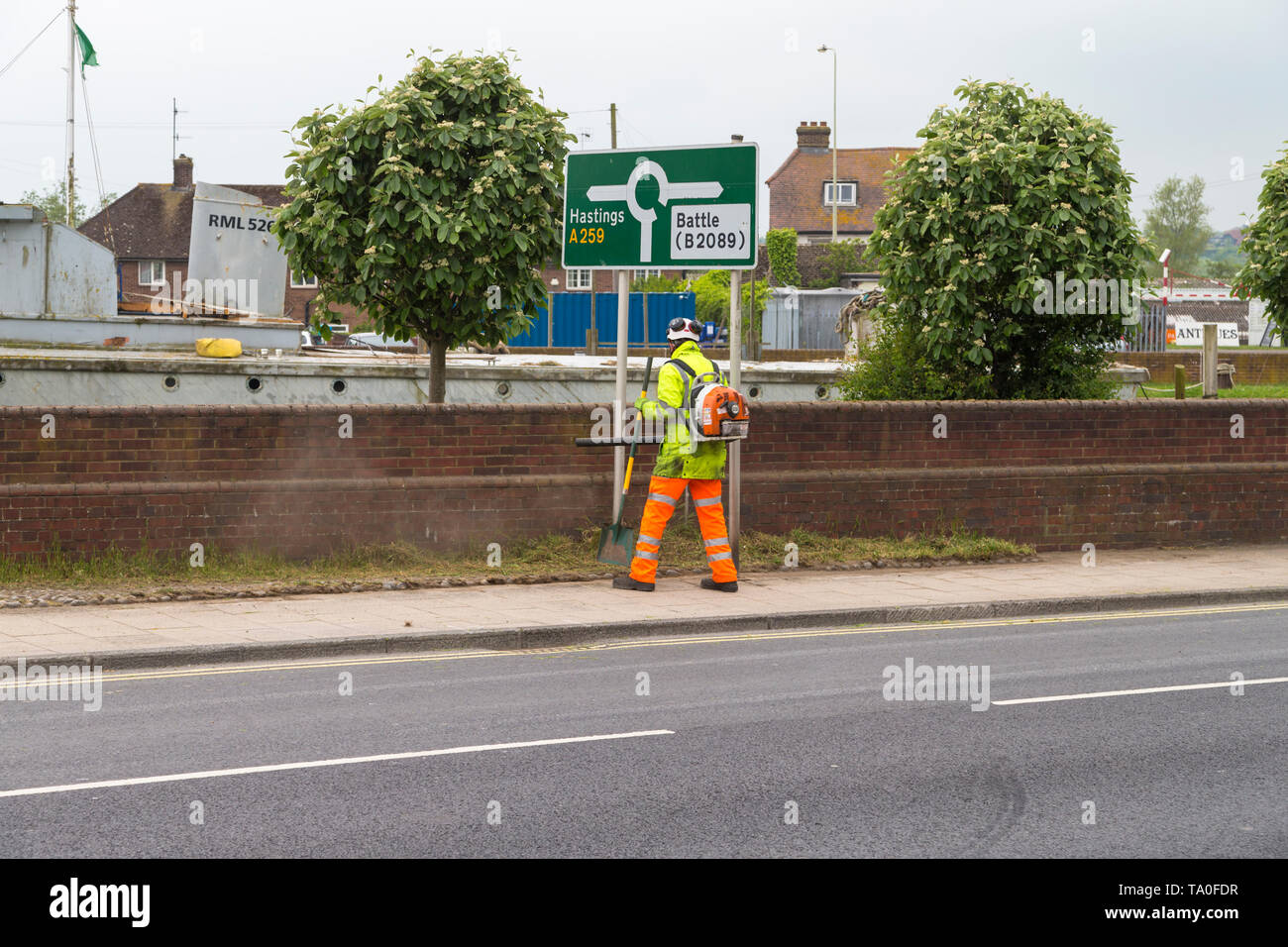 highway maintenance workman with a petrol leaf blower cleaner the walls ...