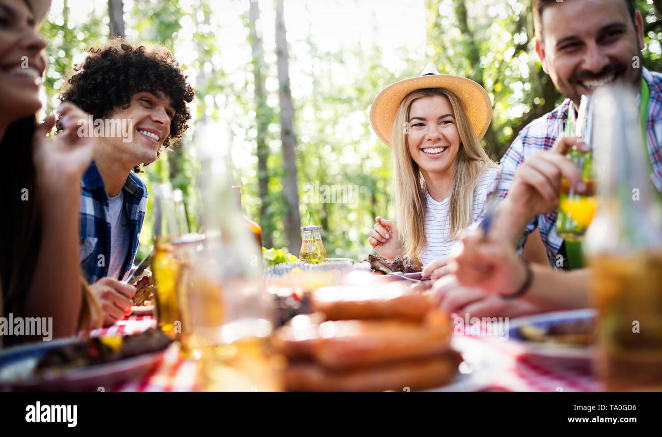 Group of happy friends eating and drinking beers at barbecue dinner ...