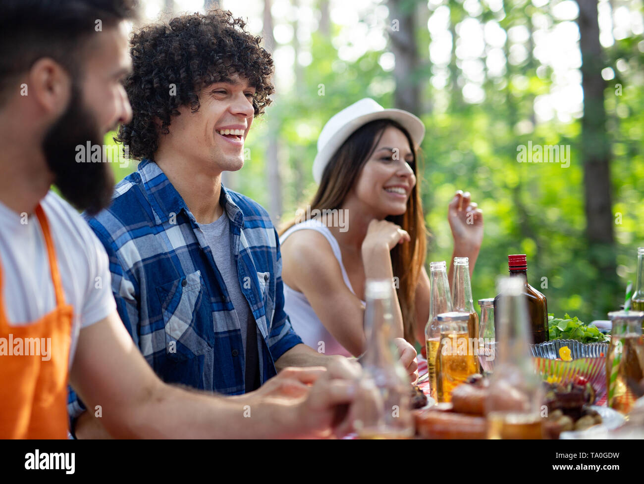 Group of happy friends eating and drinking beers at barbecue dinner ...