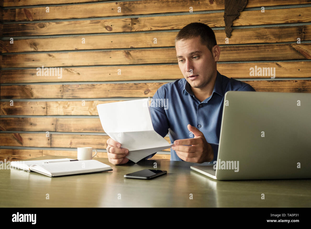 Concerned businessman reading a paper document or letter gesturing with ...