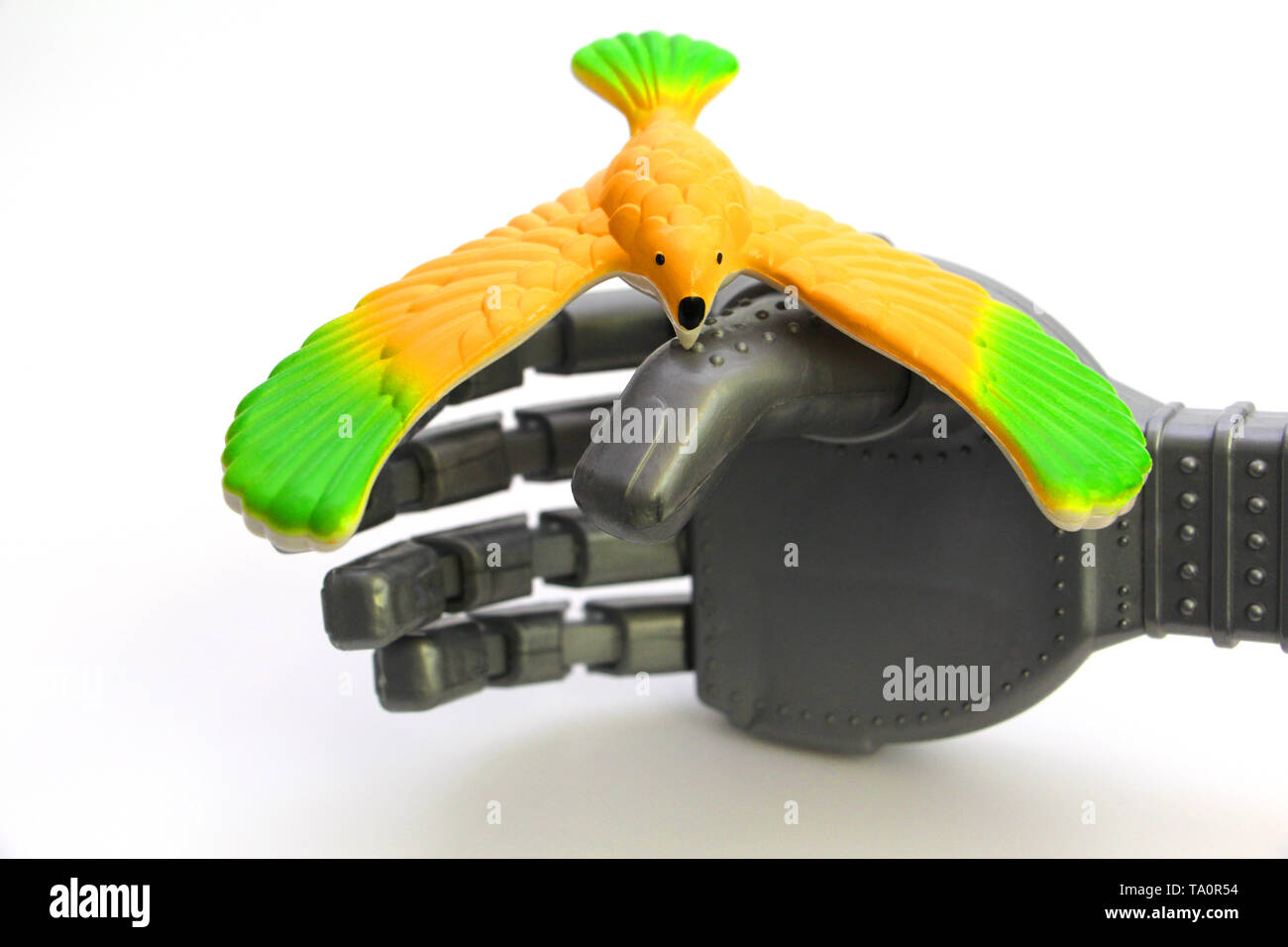 A little bird is sitting on the finger of a robot. The bird is yellow ...