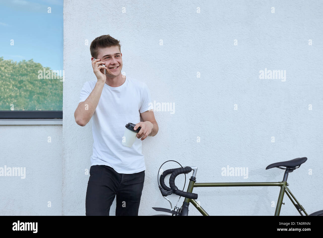 Young hipster style man posing with bicycle on the street sport style ...