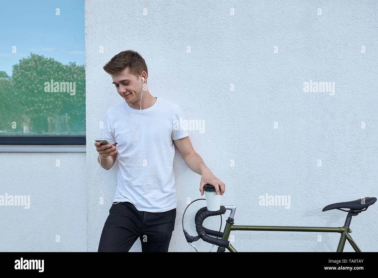 Young hipster style man posing with bicycle on the street sport style ...