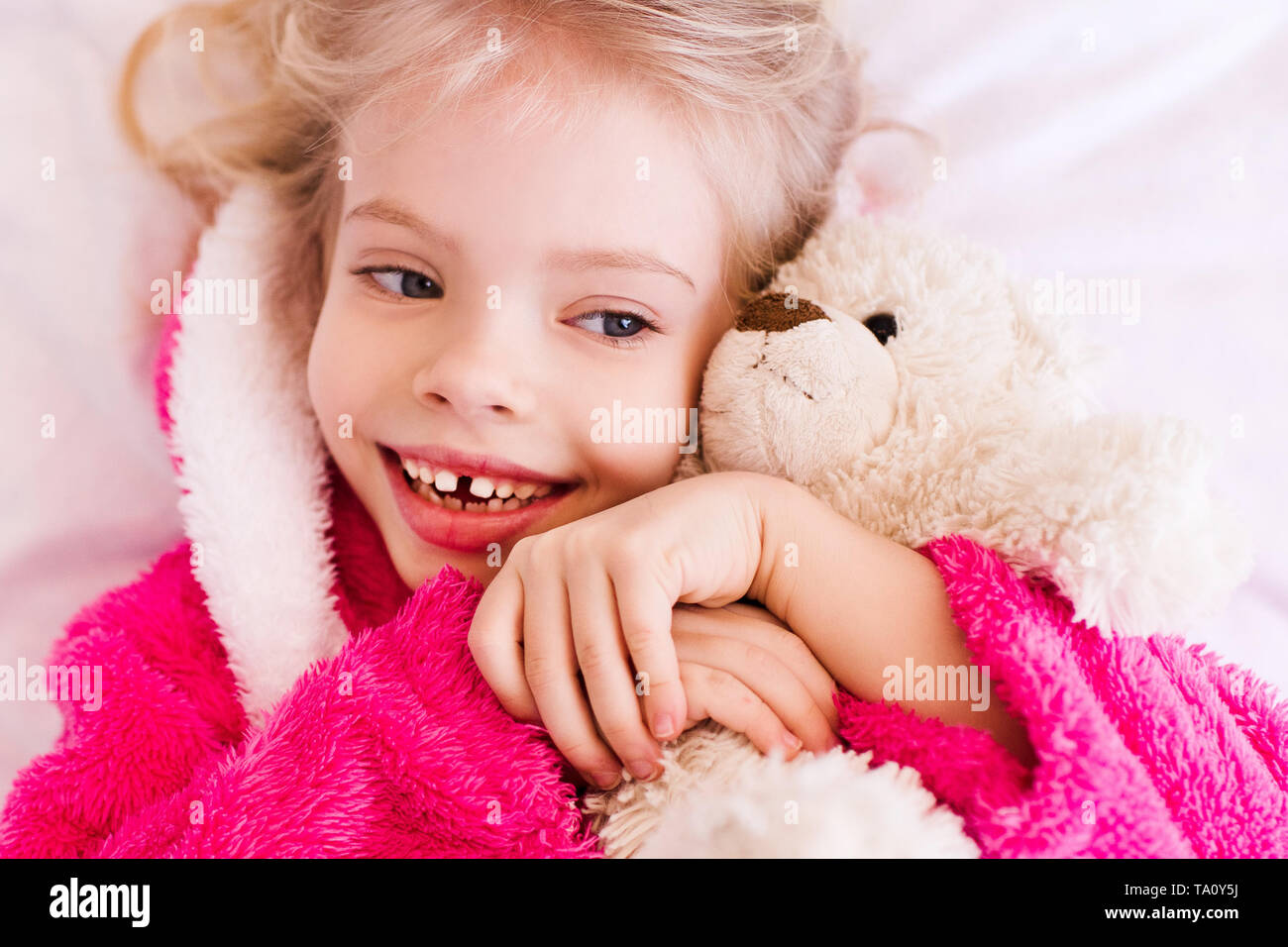 Happy baby girl 3-4 year old smiling with teddy brea in bed. Friendship ...