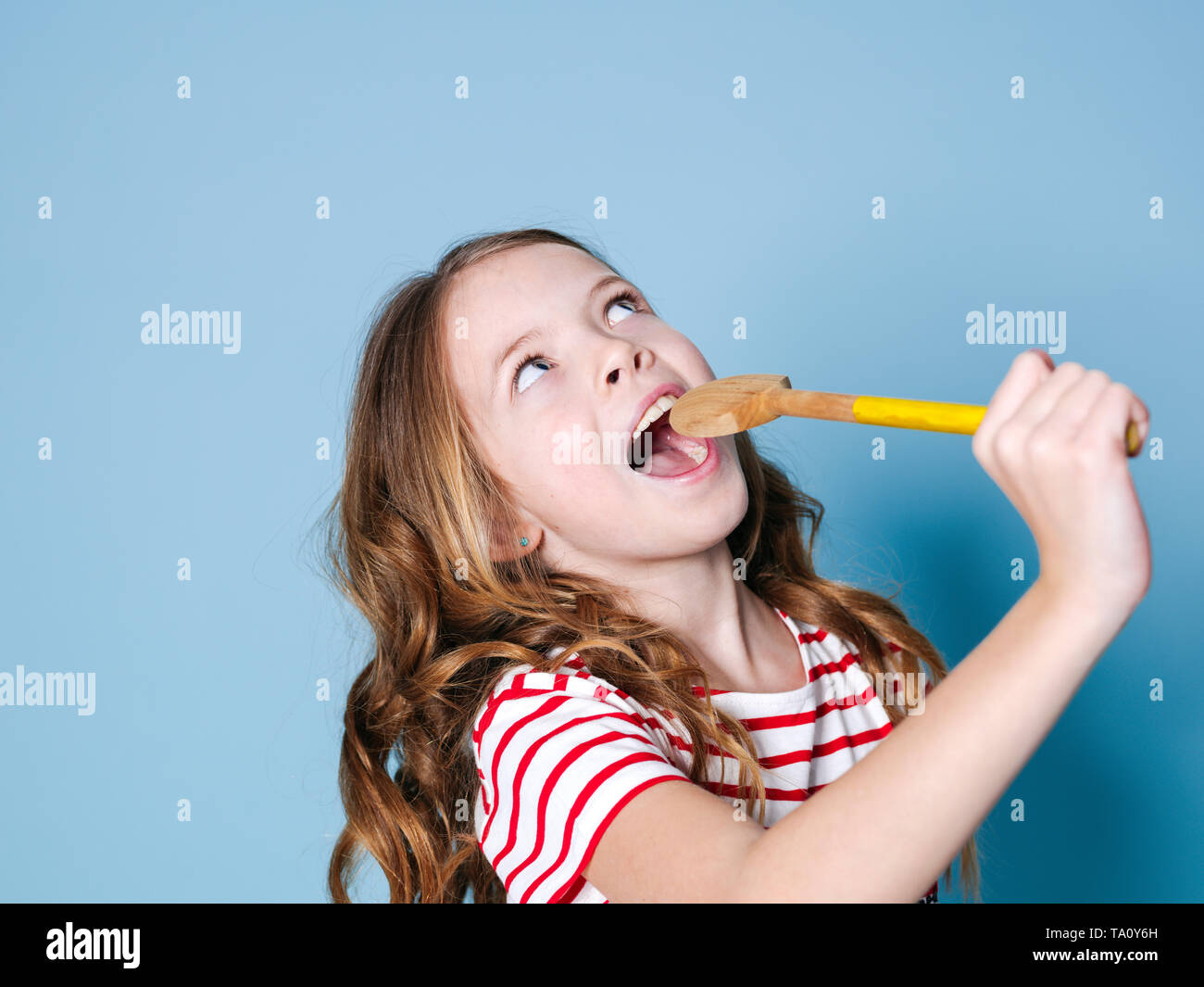 pretty cool and young girl uses cooking spoon as microphone and sings ...