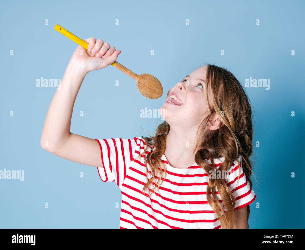pretty cool and young girl uses cooking spoon as microphone and sings ...