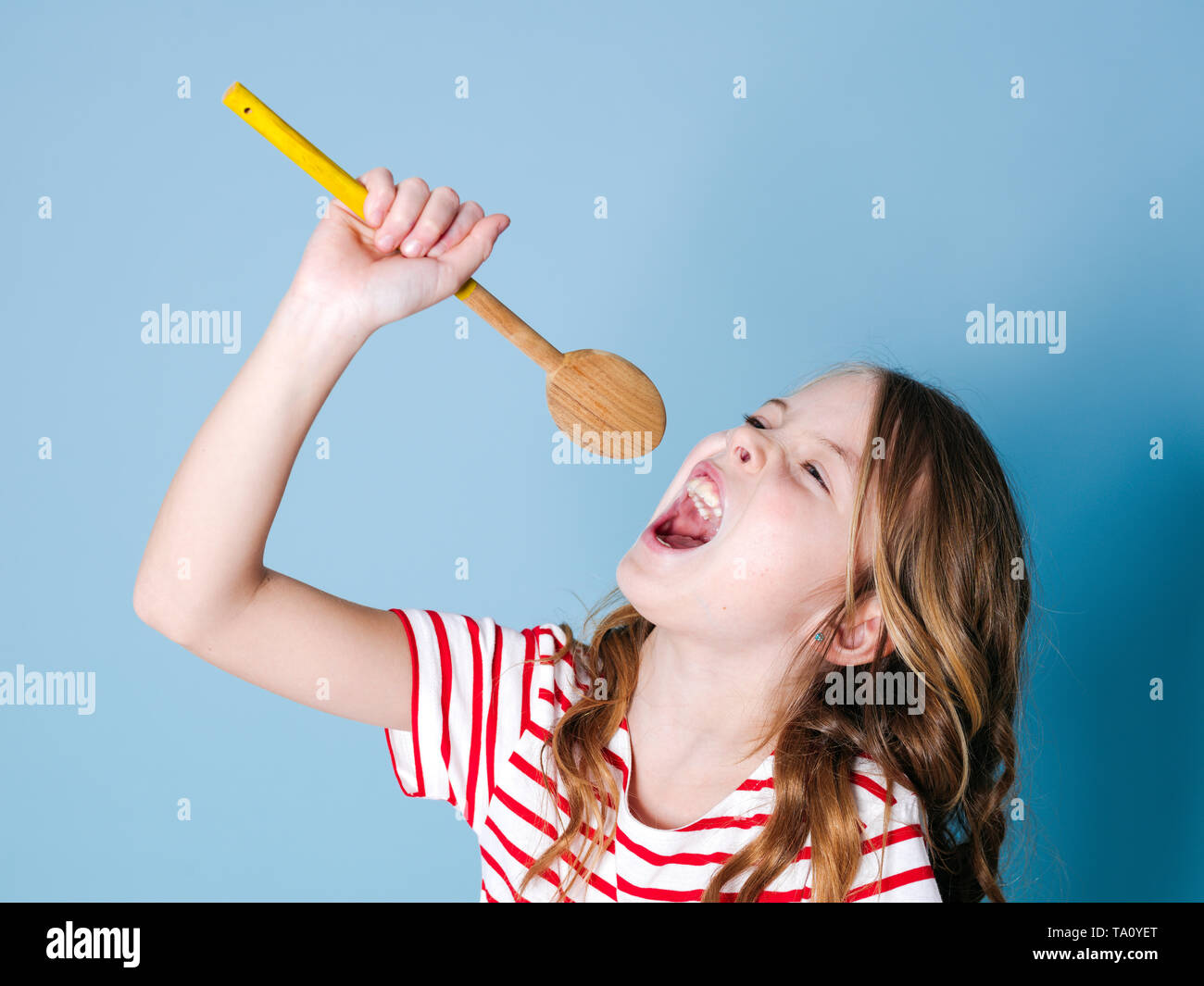 pretty cool and young girl uses cooking spoon as microphone and sings ...