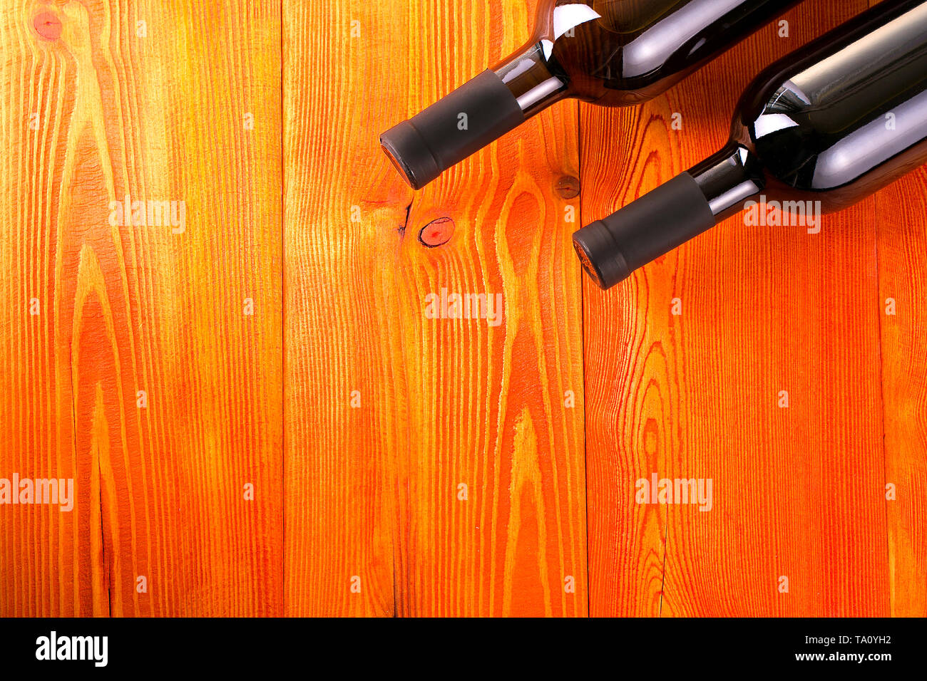 Glass bottles of wine on red wooden table background Stock Photo - Alamy