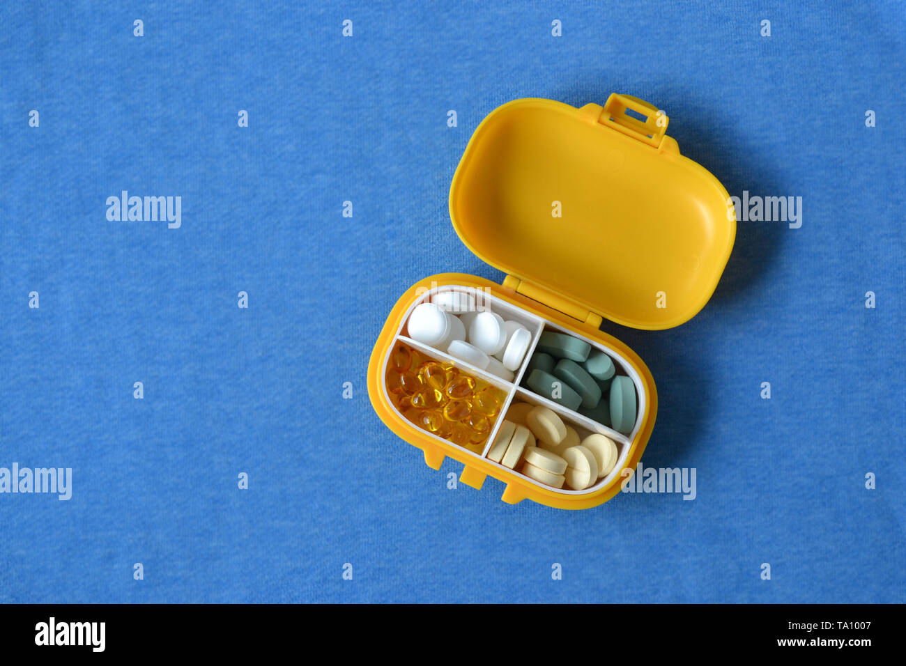 Yellow plastic medicament container with pills on blue background. Copy ...