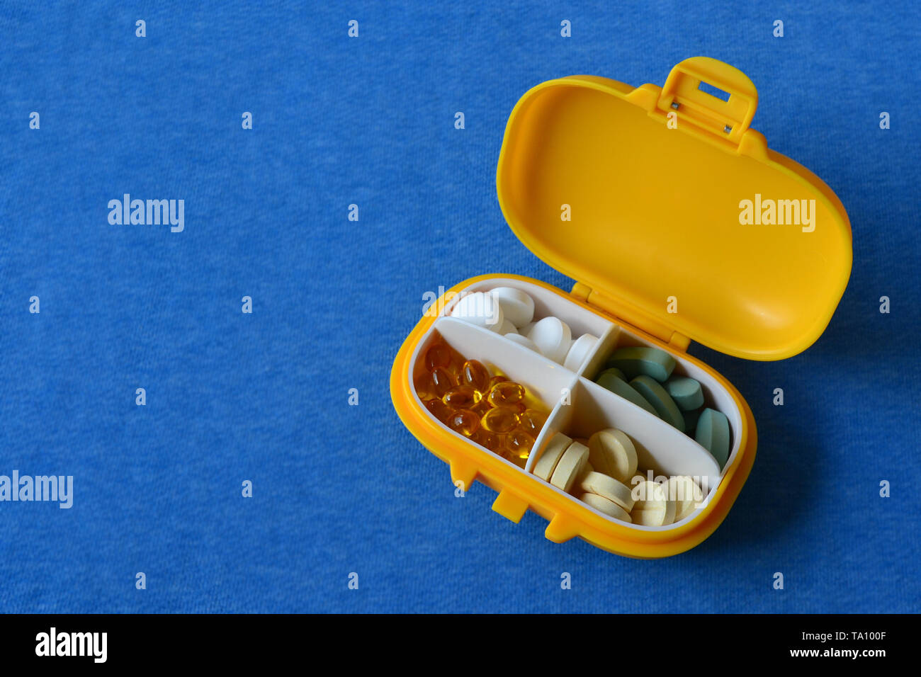 Yellow plastic medicament container with pills on blue background. Copy ...