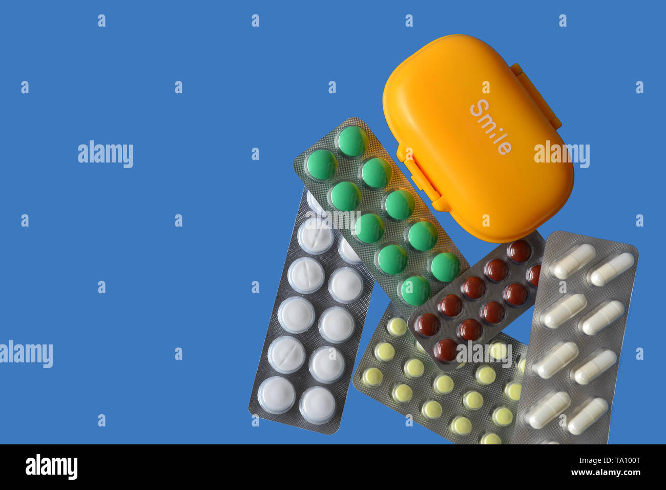 Different pills in blisters and yellow plastic medicament container ...