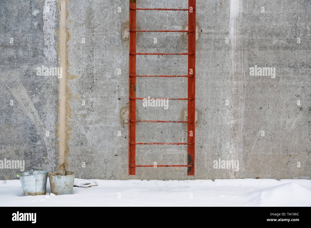 View of red metal ladder outside of a concrete building Stock Photo - Alamy