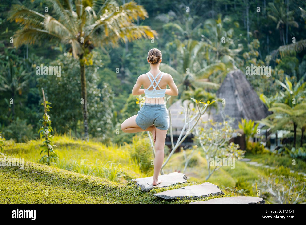 Woman on rice paddy in yoga pose Stock Photo - Alamy