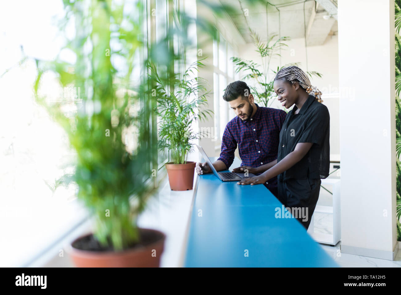 Young beautiful african woman pointing at laptop with smile and ...