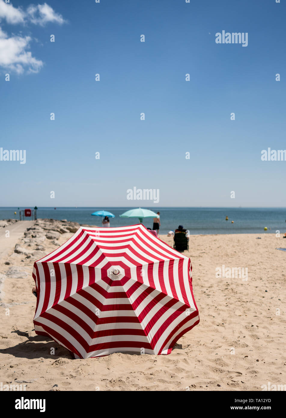 Striking red striped sun umbrella sun shade on the beach at Sandbanks ...