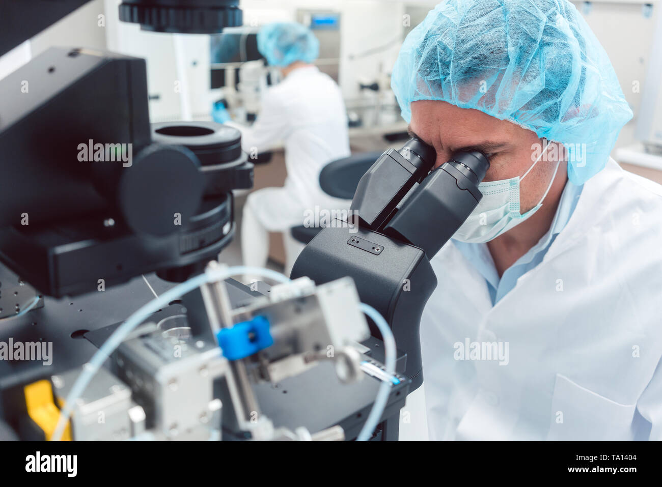 Doctor or scientist looking thru microscope in lab Stock Photo - Alamy