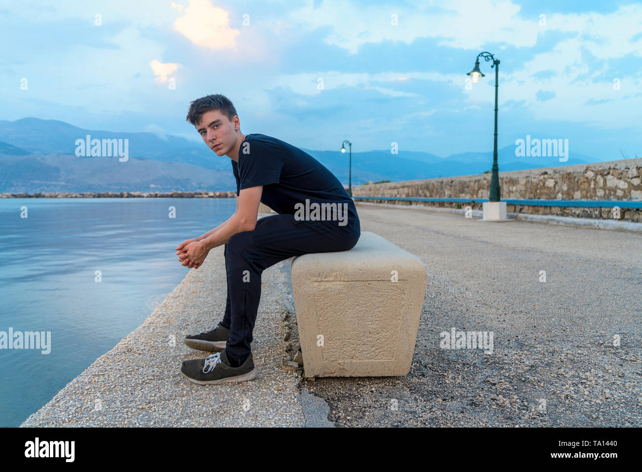 portrait of a young man sitting on a pier Stock Photo - Alamy