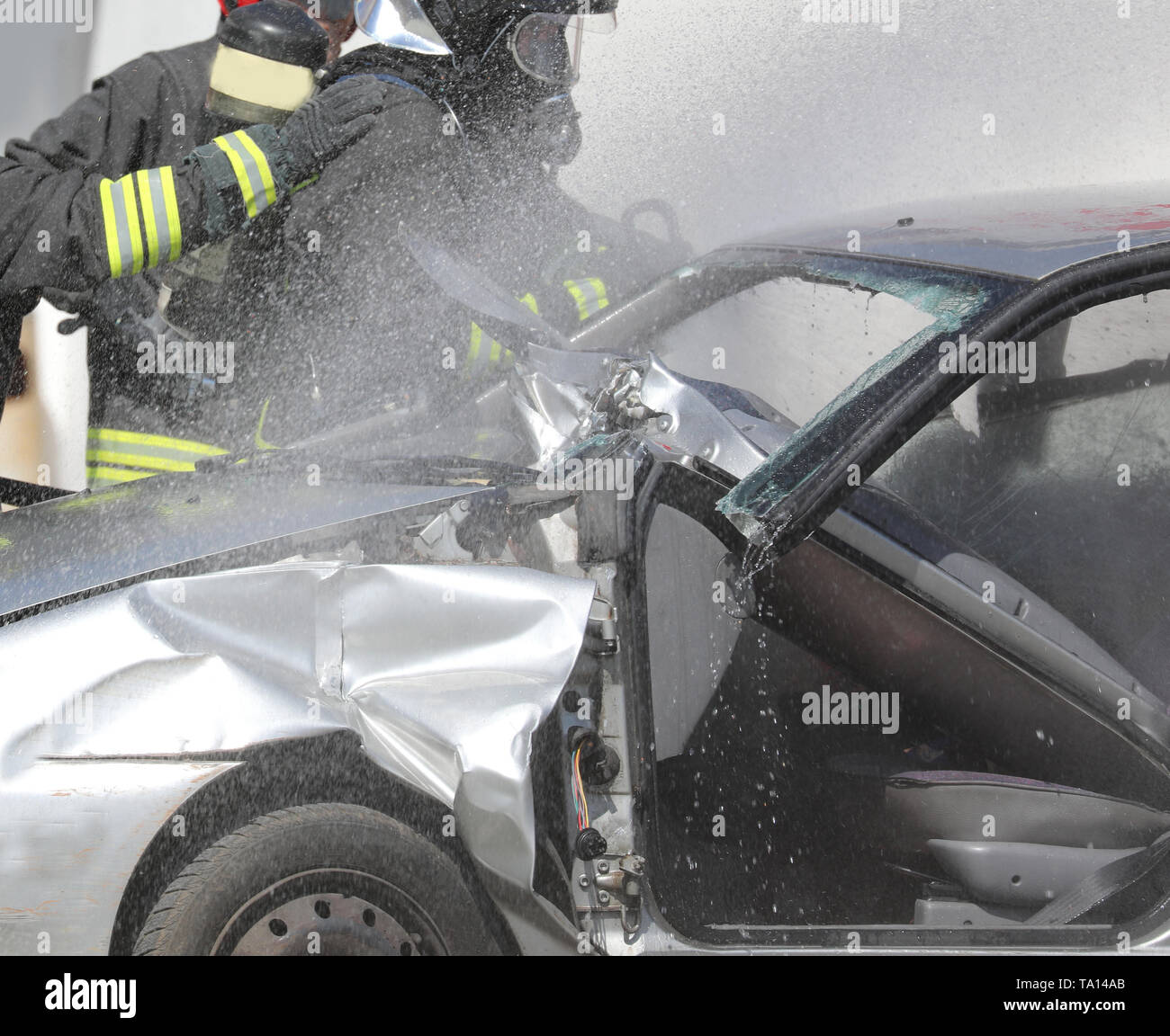 fire brigade team during the fire extinguishing of a destroyed car ...